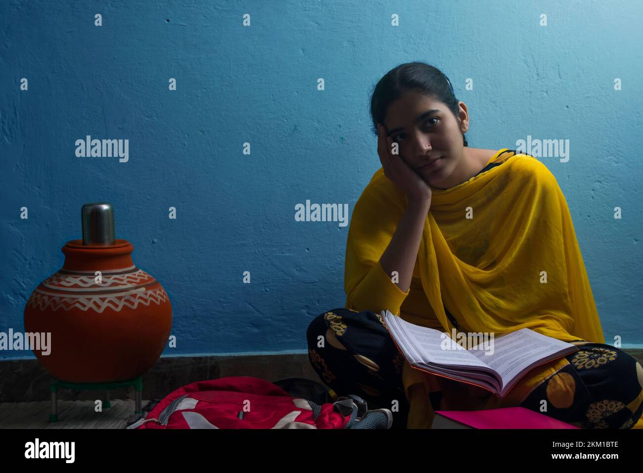 A girl in school uniform thinking while studying at home Stock Photo ...
