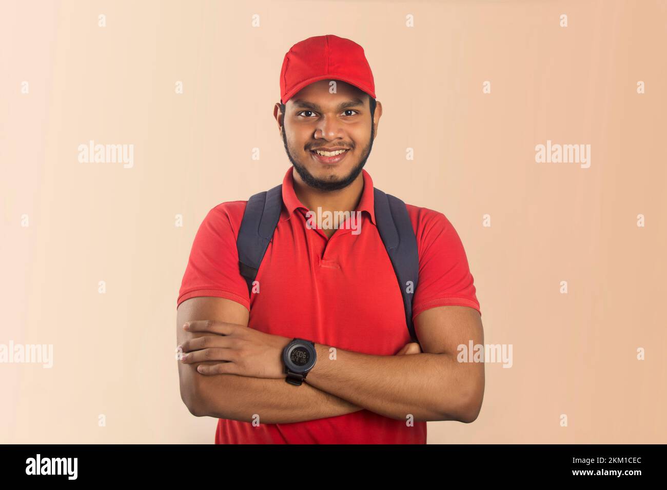 Portrait of a confident young delivery man standing with arms folded ...