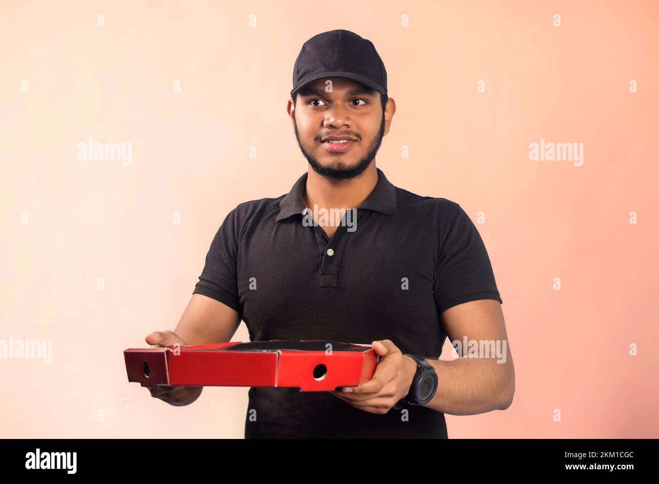Portrait of delivery man carrying Pizza box against Color background ...