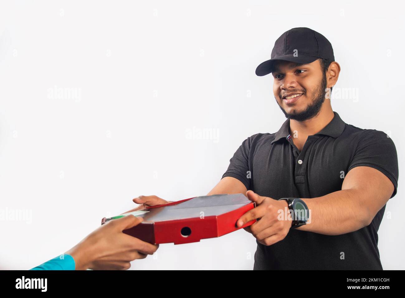Young delivery man in black uniform and cap holding box package giving ...