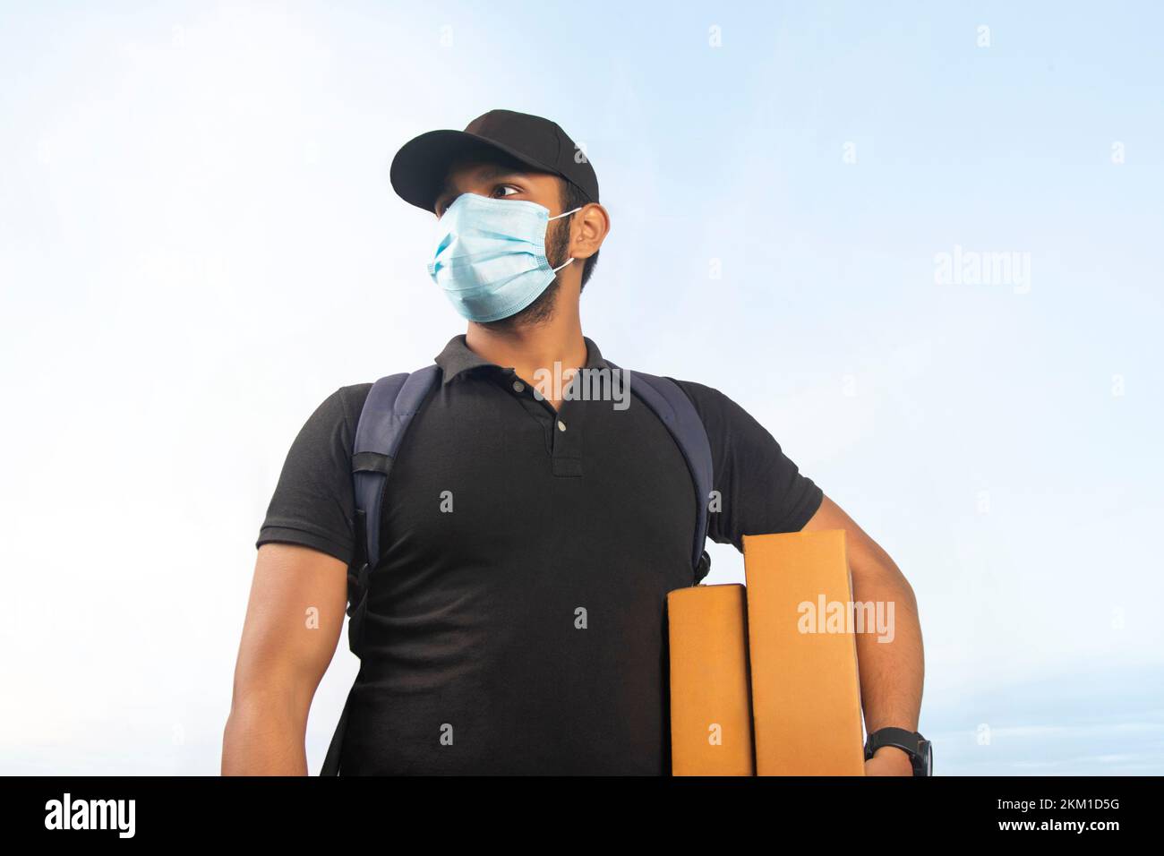 Portrait Of Young Delivery Man wearing face mask Holding Cardboard Box ...
