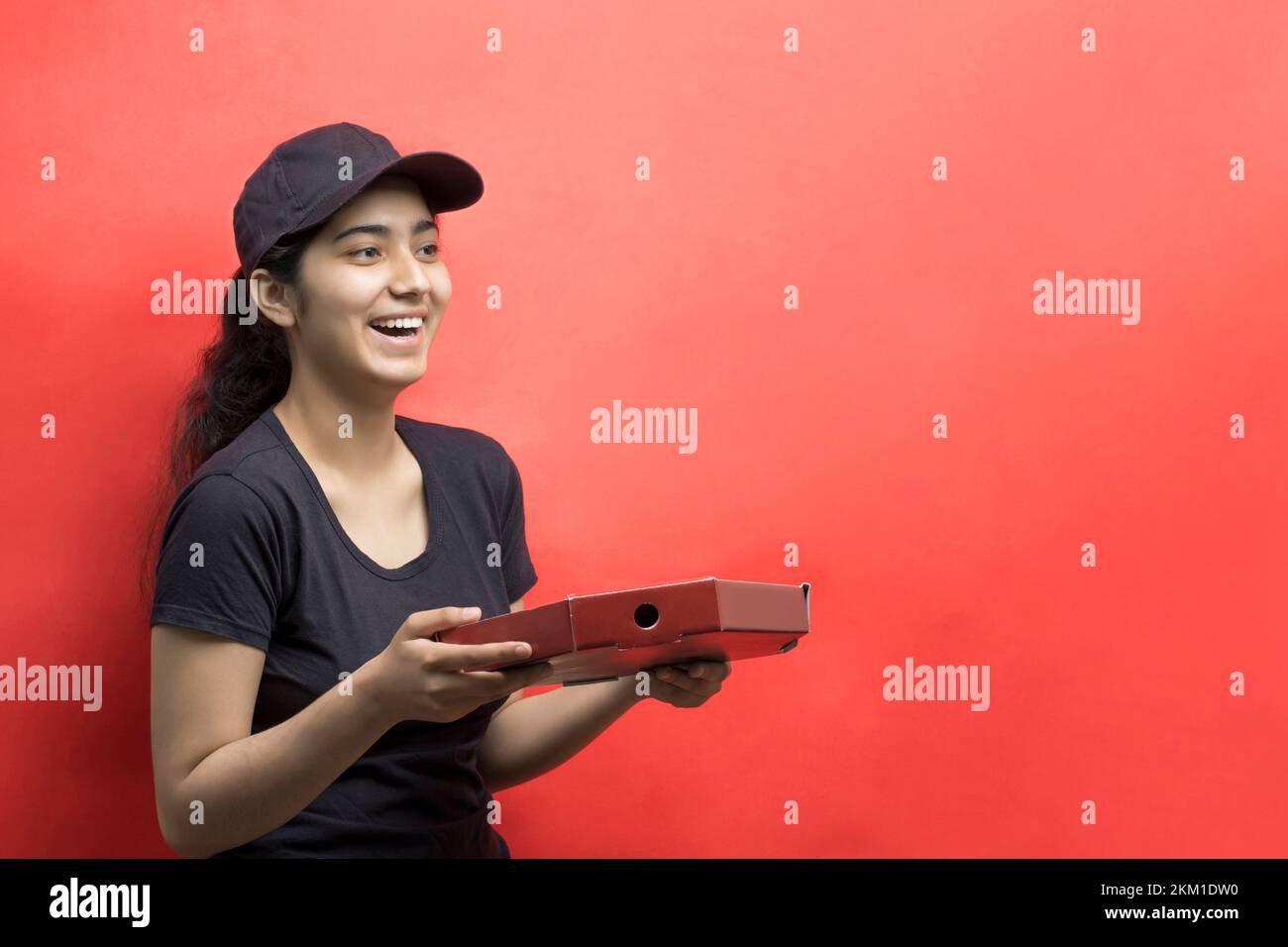 Happy delivery woman carrying Pizza box against Color background Stock ...