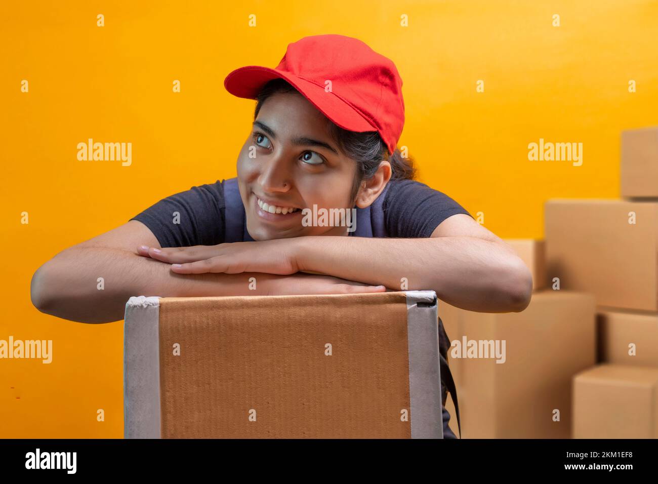 Smiling Delivery Woman Lying On Parcel Box and looking elsewhere Stock ...