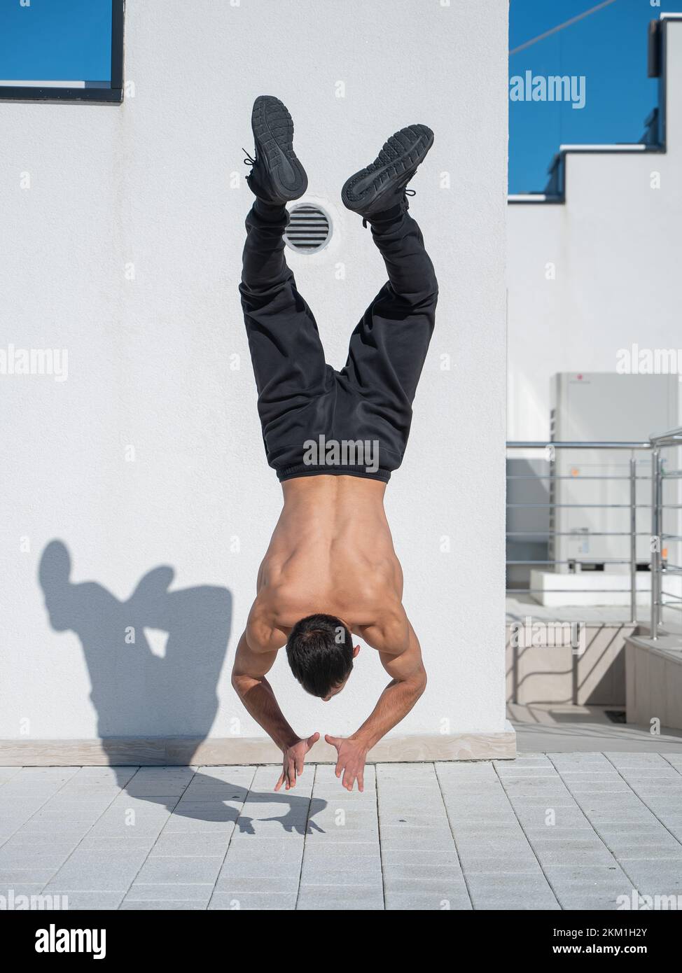 Man doing a handstand outdoors against a white wall Stock Photo - Alamy