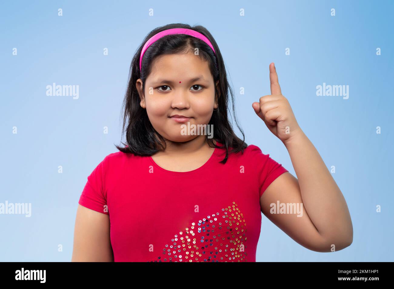 Portrait of girl smiling for having good idea with finger pointing up ...