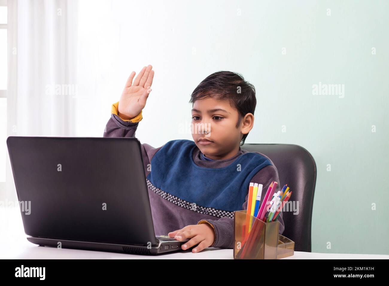 Boy using laptop and waving during video call while homeschooling Stock ...