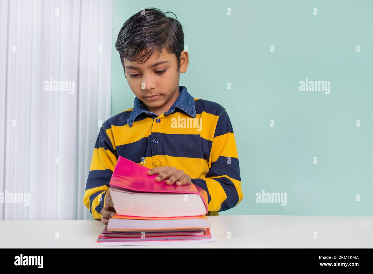 Indian boy reading book over study table at home Stock Photo - Alamy