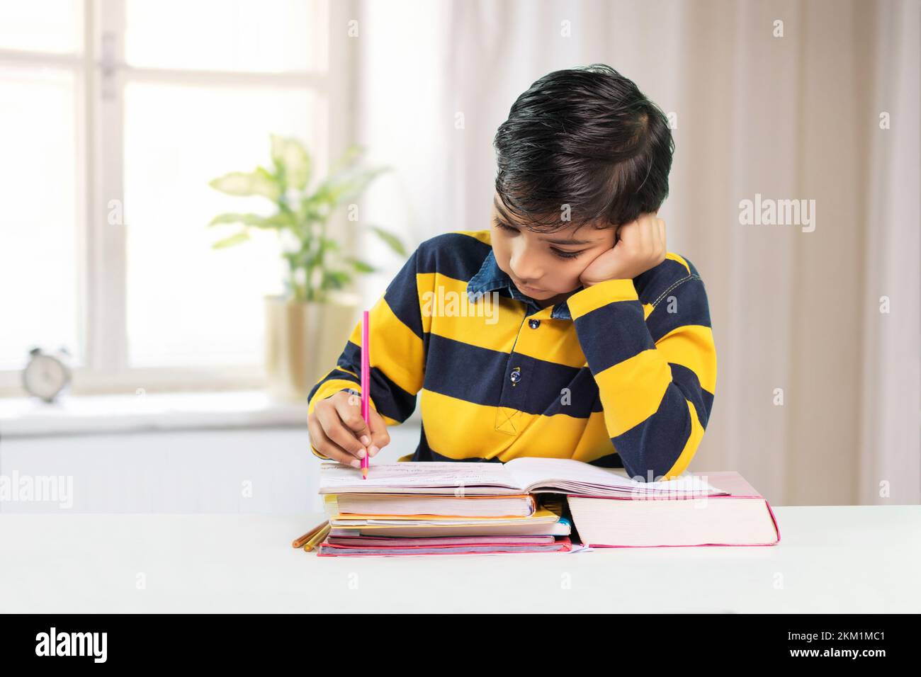 Indian boy student doing study at home, He is writing on notebook and ...