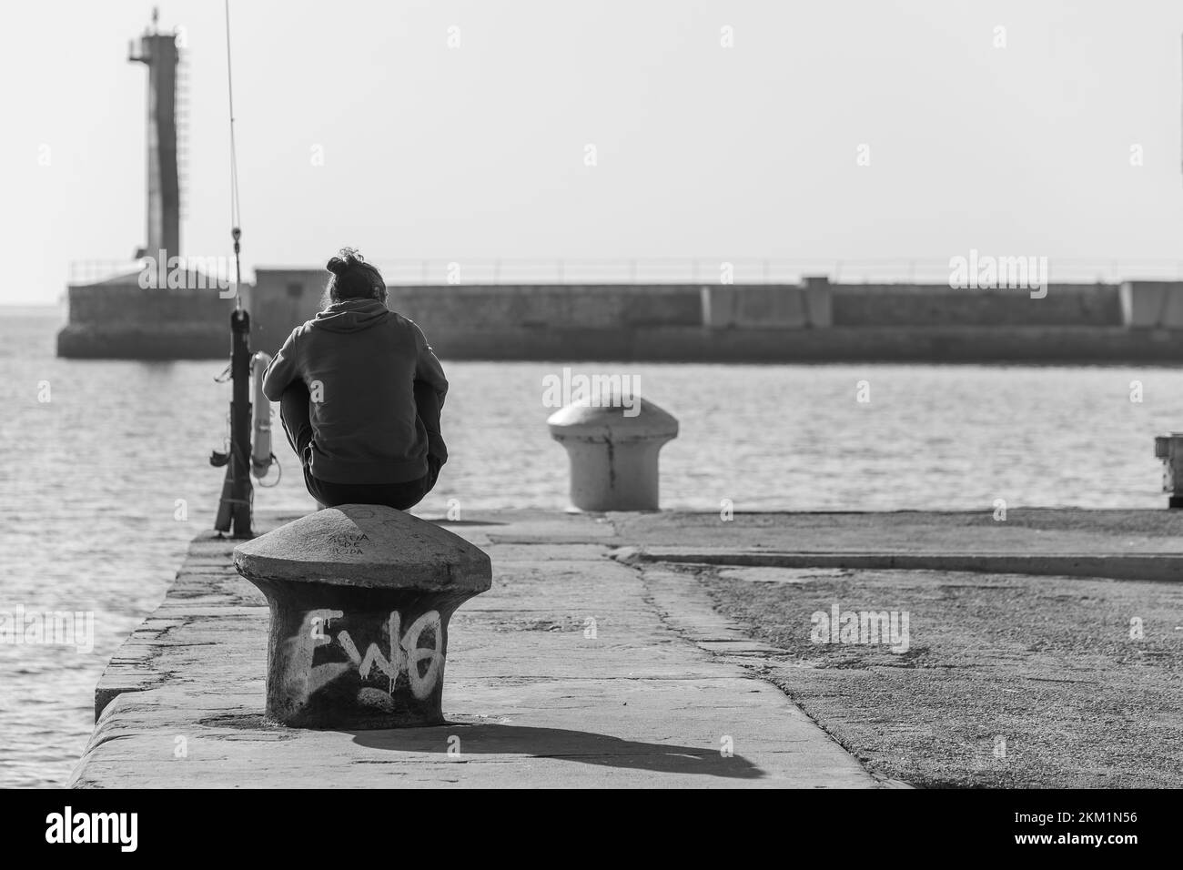 Guy sitting at hte edge of a pier talking on the phone Stock Photo - Alamy