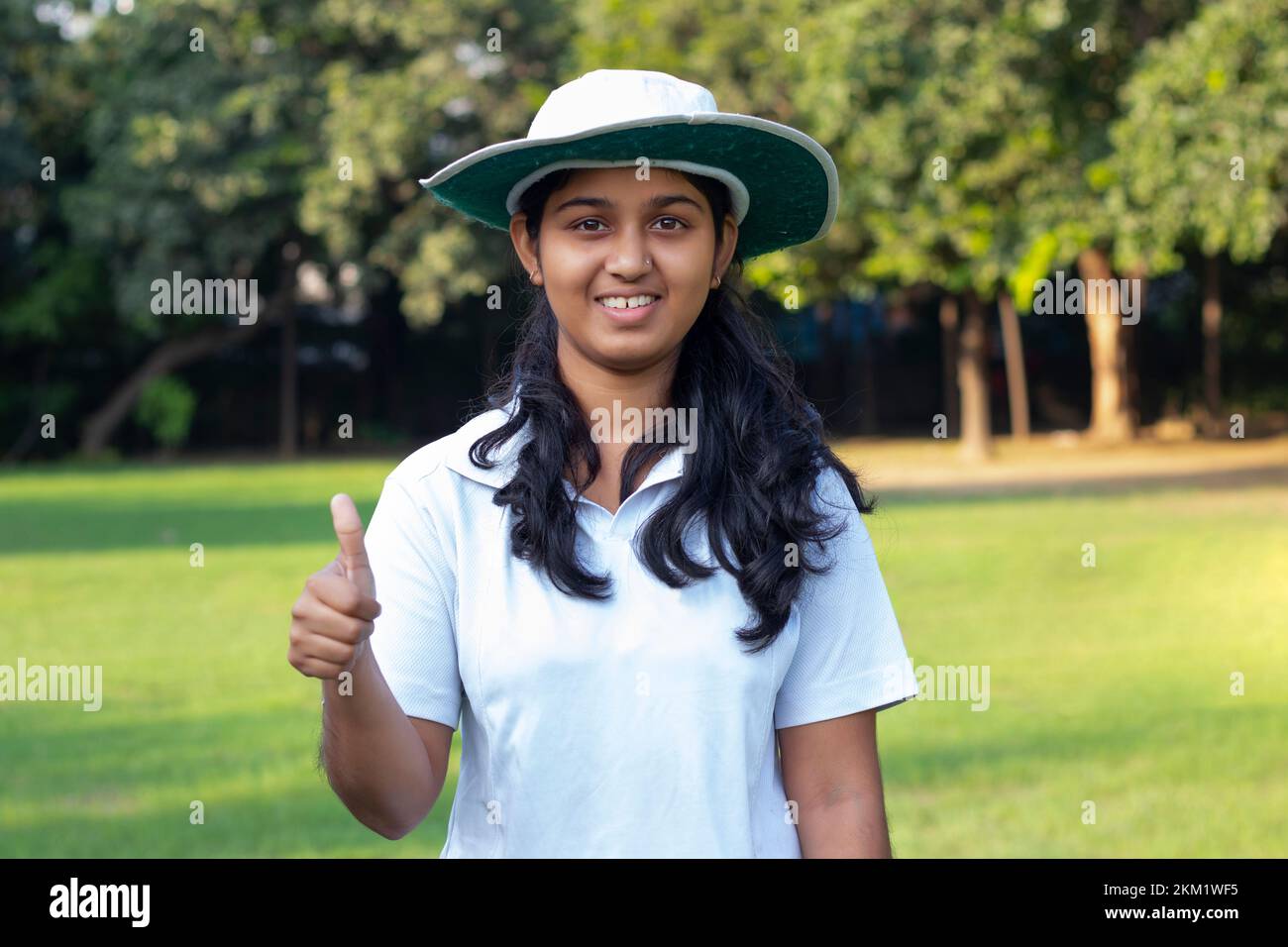 a girl wearing cricket uniform and thumbs up standing in outdoor Stock ...