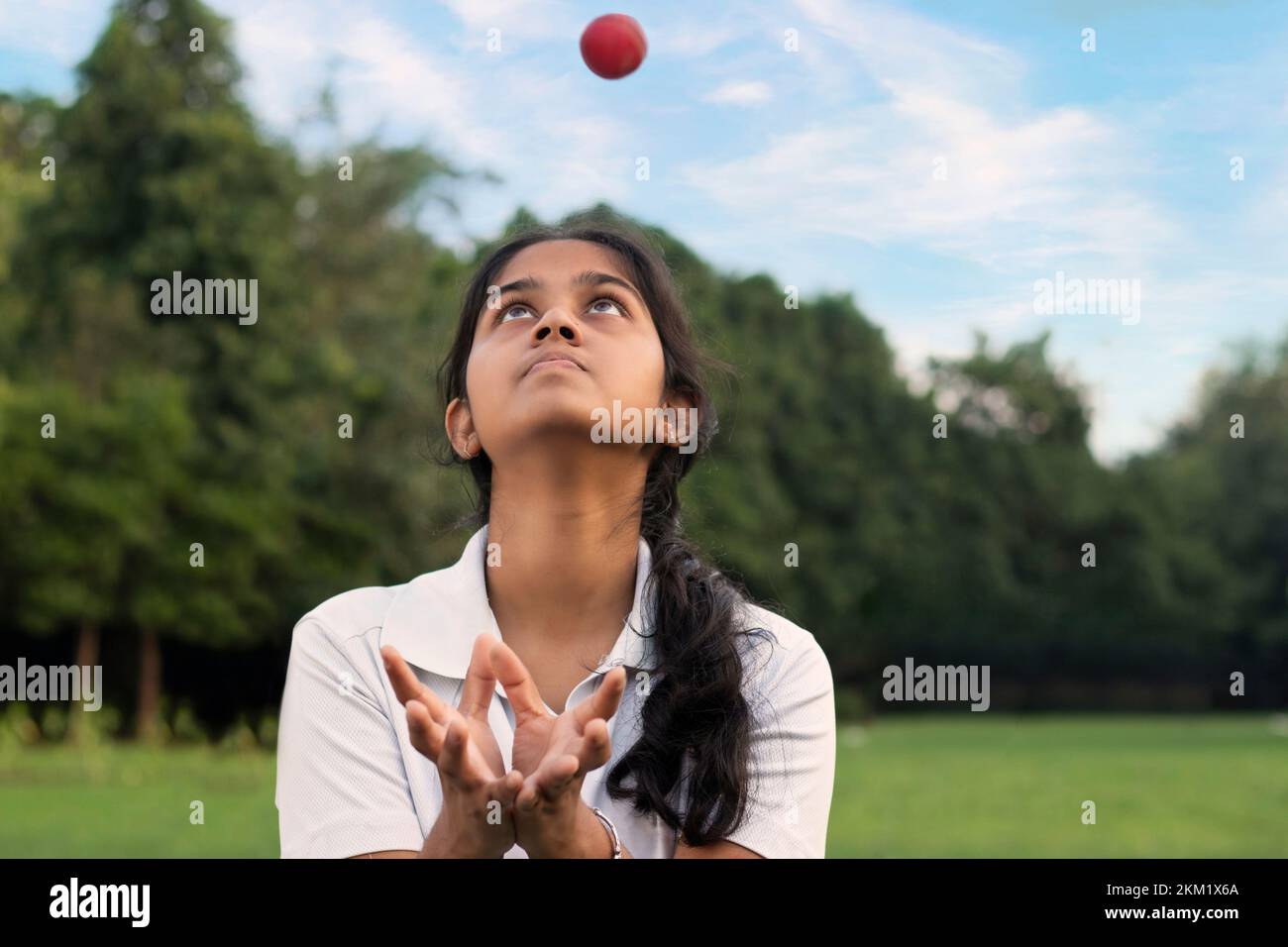 Girl wearing cricket uniform catching the ball on the field Stock Photo ...