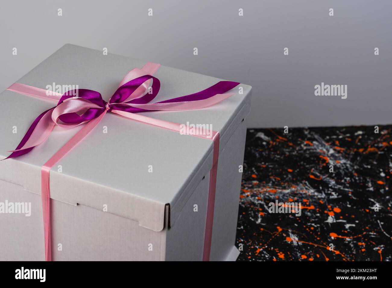 white gift box tied with a red ribbon on a spotted colored background ...