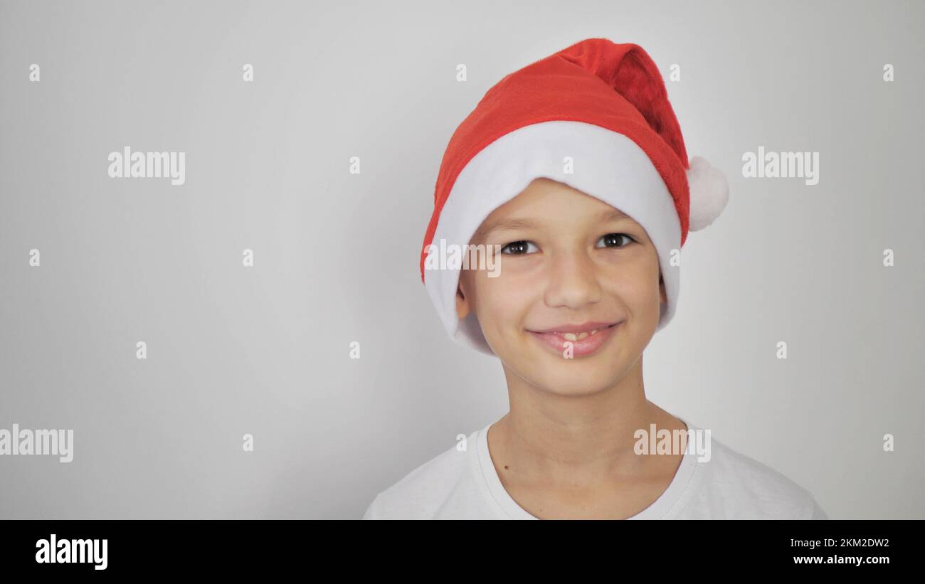 a child in a white T-shirt and a red Santa Claus hat. empty copy space ...