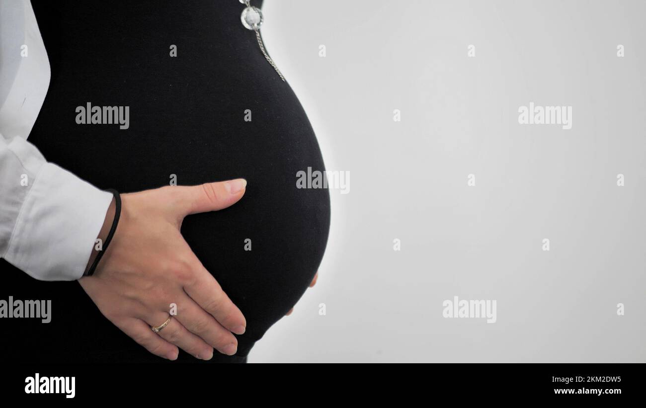 Side view of a pregnant woman holding her hand on her tummy. Isolated ...