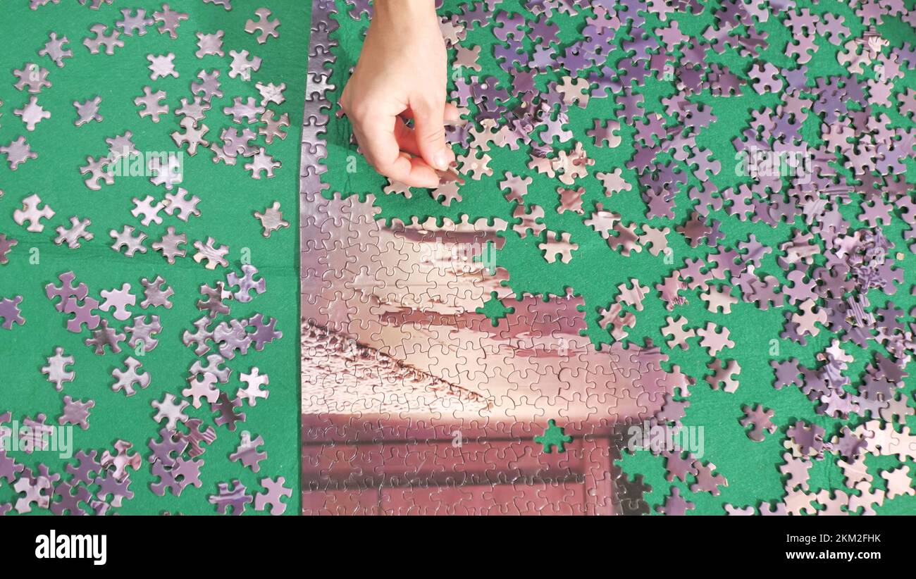 A woman hands, putting together pieces of a puzzle. Stay at home ...