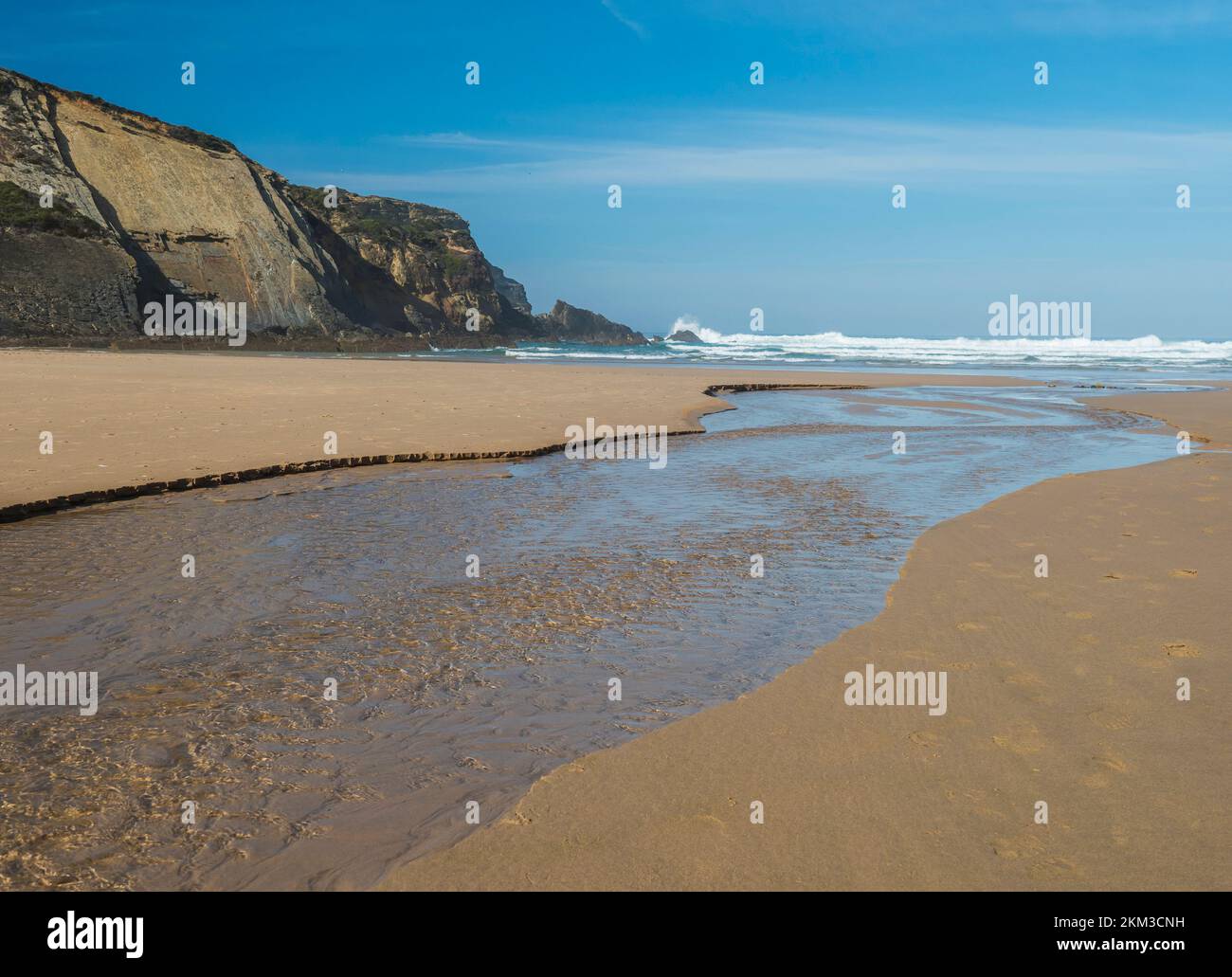 View of empty Praia do Carvalhal beach with small stream leading to ...