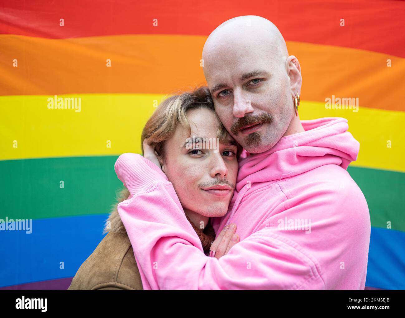 Two young men activist of the Lgbt movement, rainbow flag on background ...