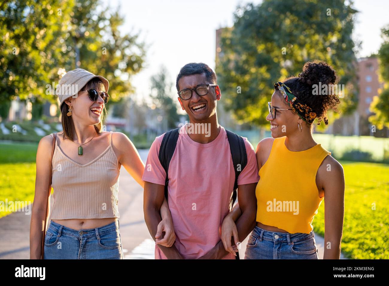 Happy people of generation z walking in a city park, handsome young man ...