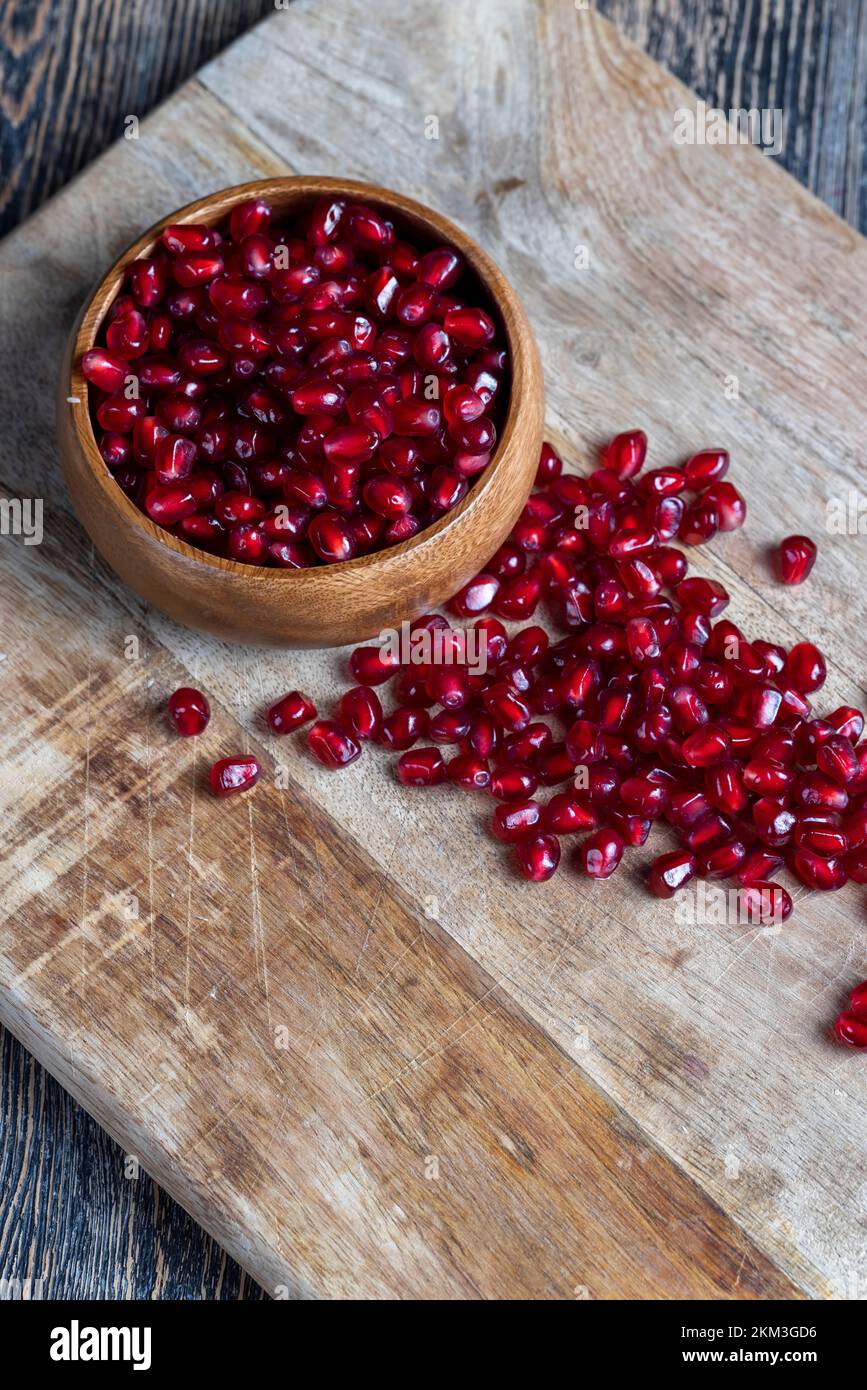 scattered pomegranate seeds on a wooden board, red ripe pomegranate ...