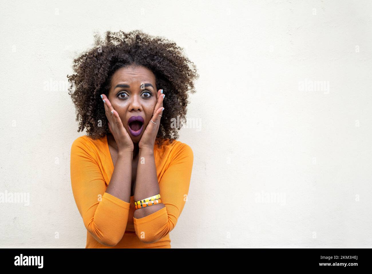 young African woman with hands to her face while screaming in awe and ...