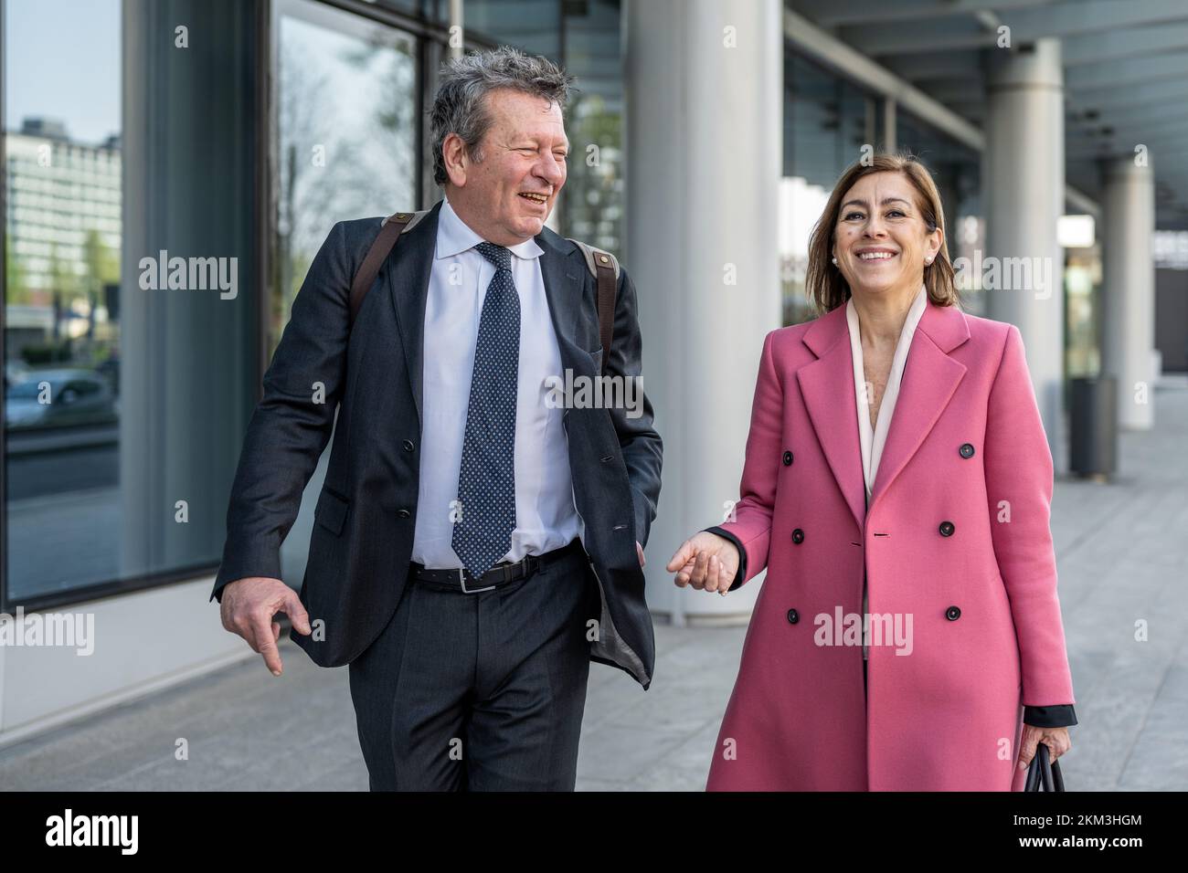 Confident business partners walking down the city and talking about ...