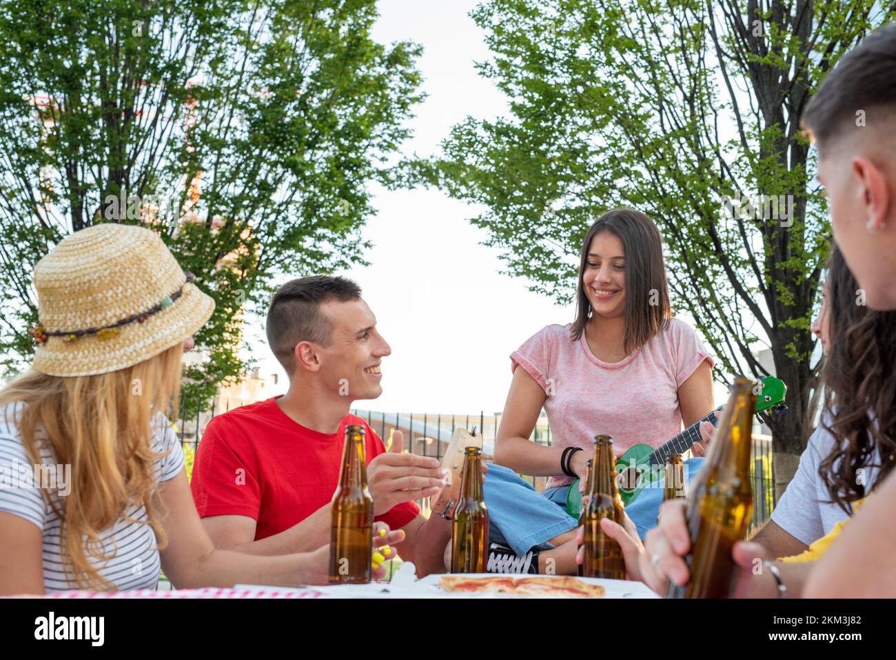 people having fun around a wooden table with take away pizza and ...