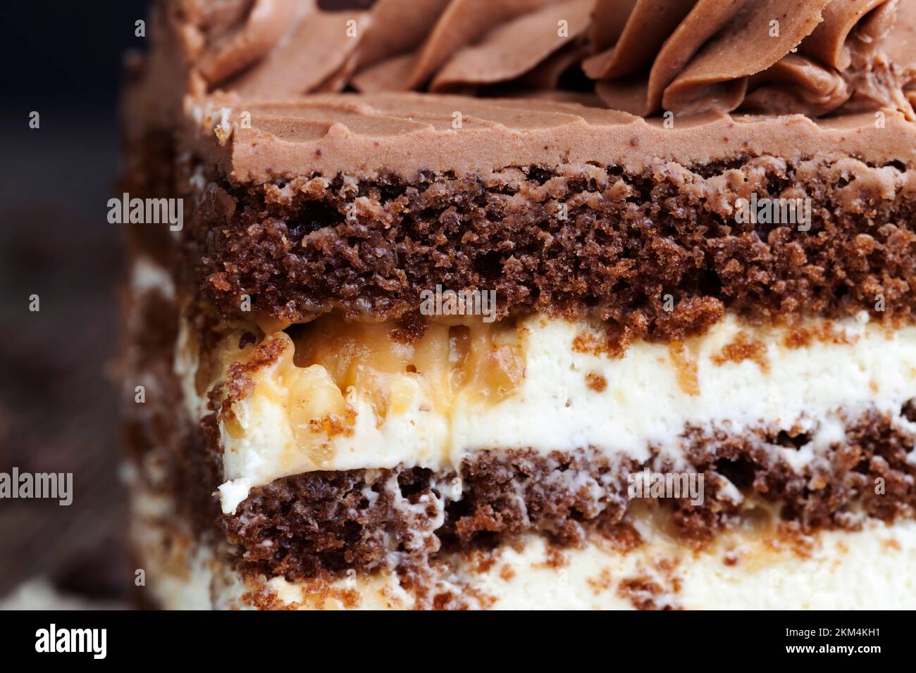 layered cake with chocolate cakes, caramel cream and hazelnuts, a piece ...