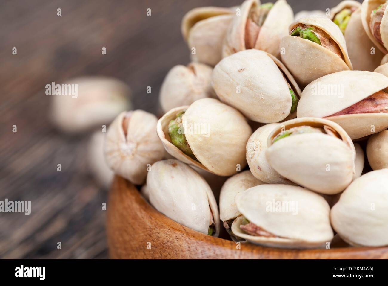 delicious fried salted pistachio nuts, pistachios on a wooden table ...