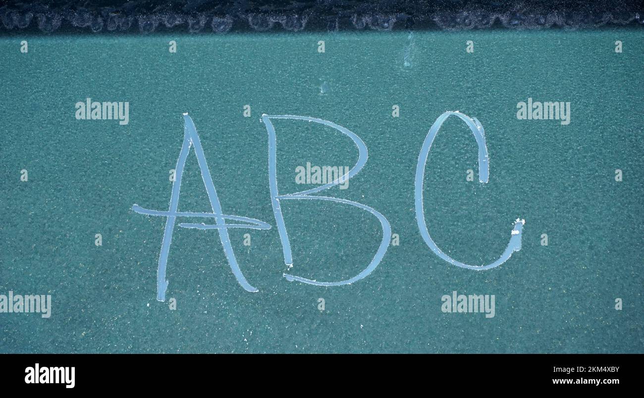 text abc written on the frozen window of a car in cold november morning ...