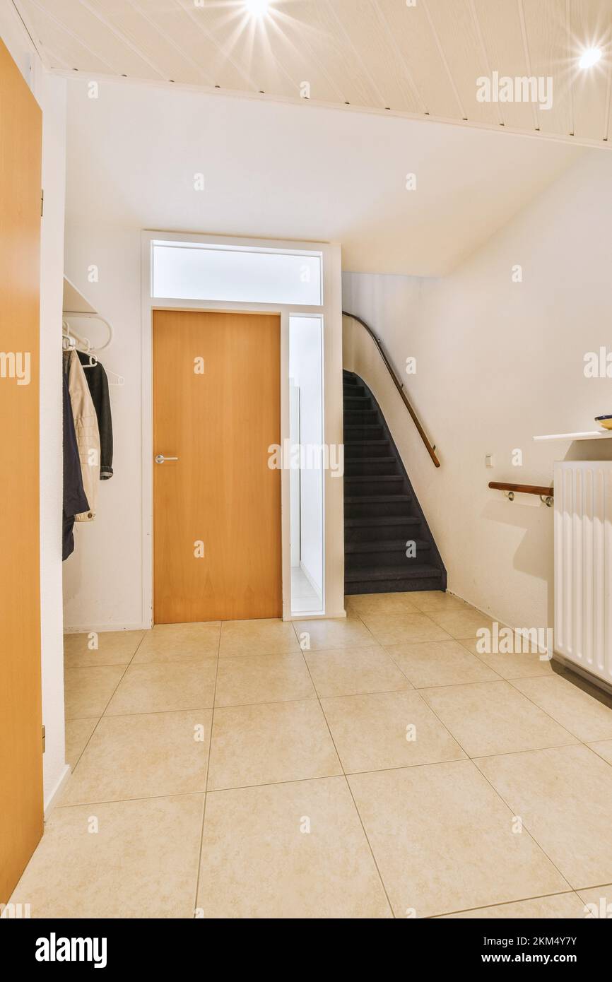 White hallway with wooden stairway leading to second floor of modern ...