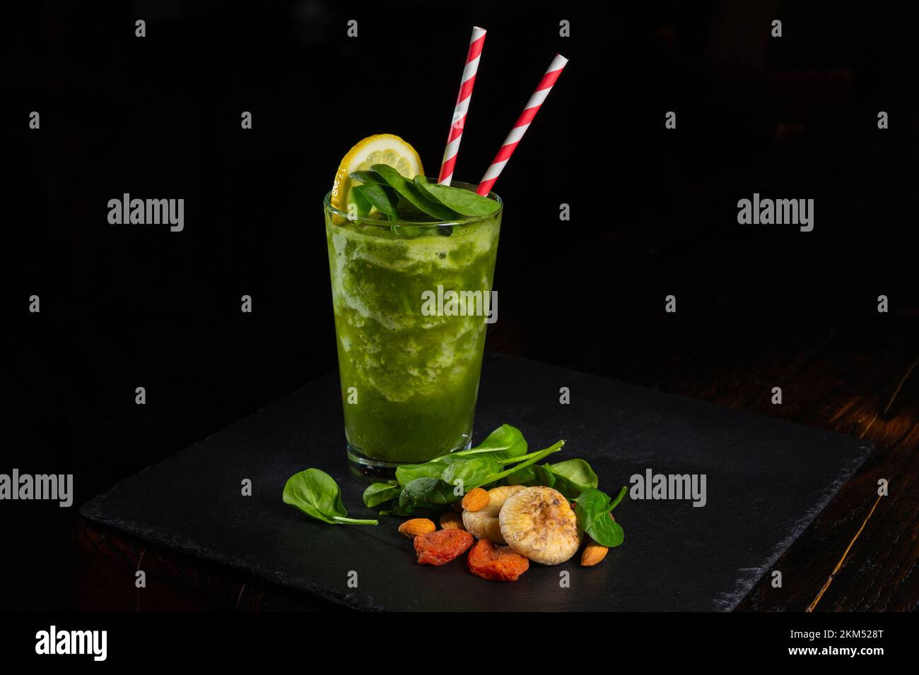 Side view of green smoothie with leaves of fresh spinach on the bar ...