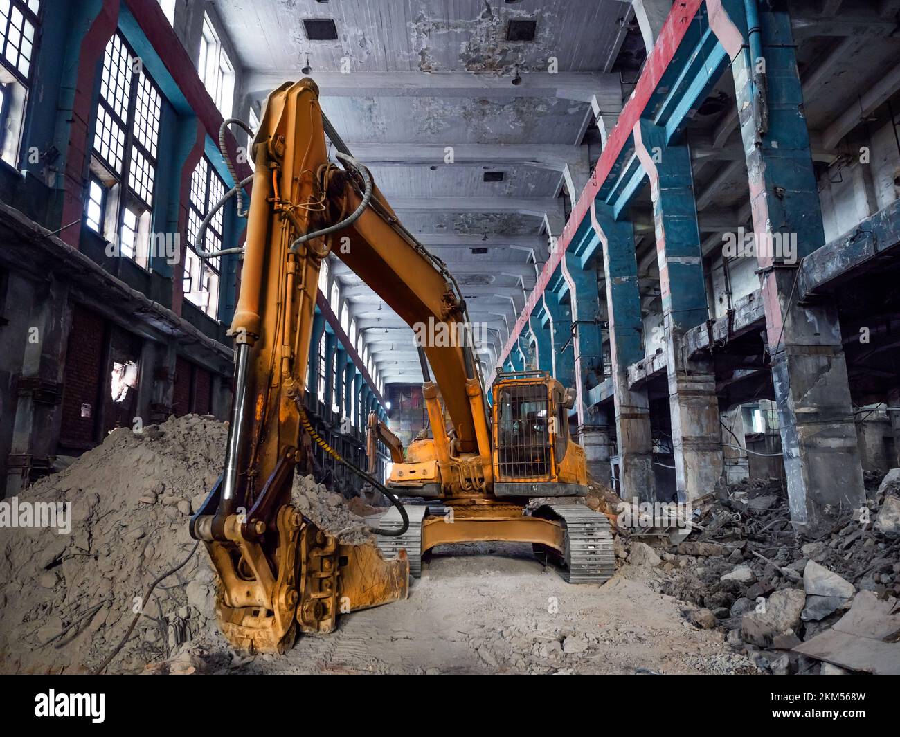 Yellow excavator during the dismantling of the old production hall ...