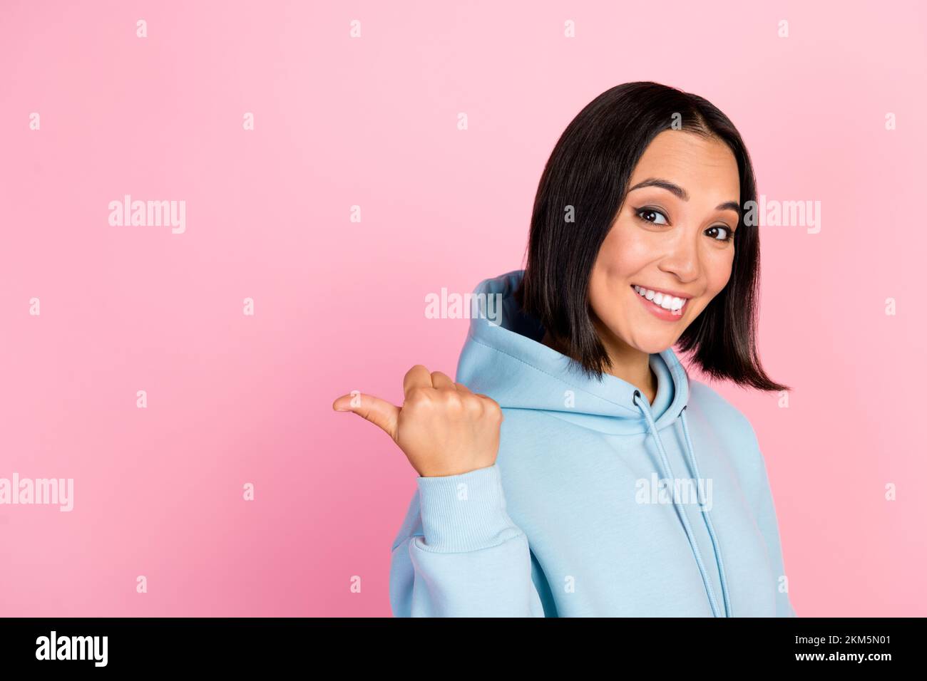 Photo of cheerful funny lady wear blue hoodie pointing thumb back empty ...