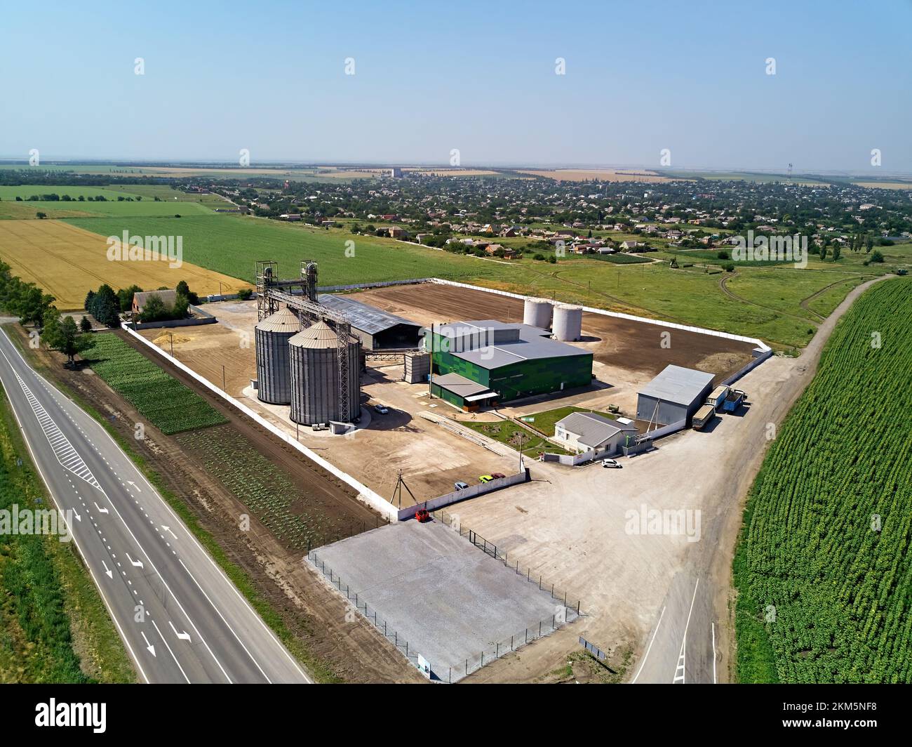 Aerial of grain elevator in front of wheat field. Drone photo above flour mill or oil extraction ...