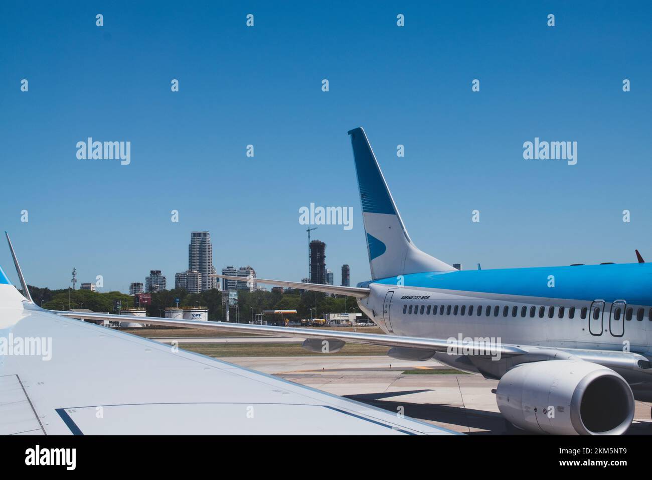 The tail end of a large airplane, parked at the gate, with the city of ...