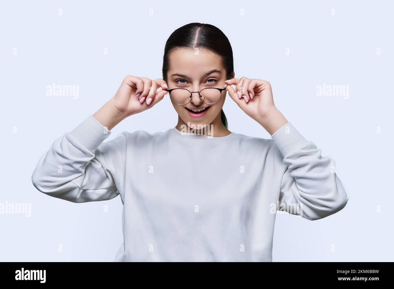 Teenage girl student holding glasses looking at camera on white ...