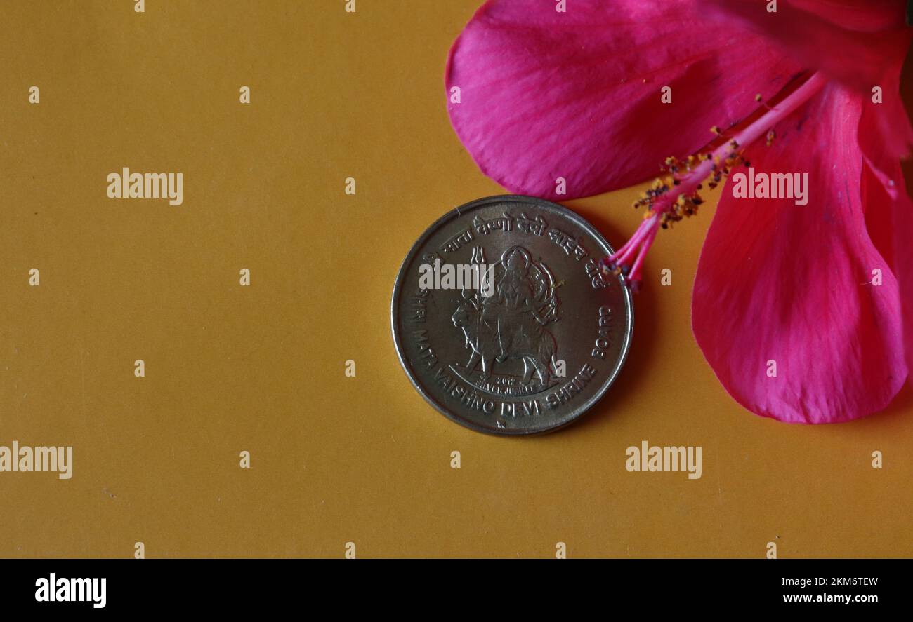 Close-up of Shree Mata Vaishno Devi coin and hibiscus flower against ...