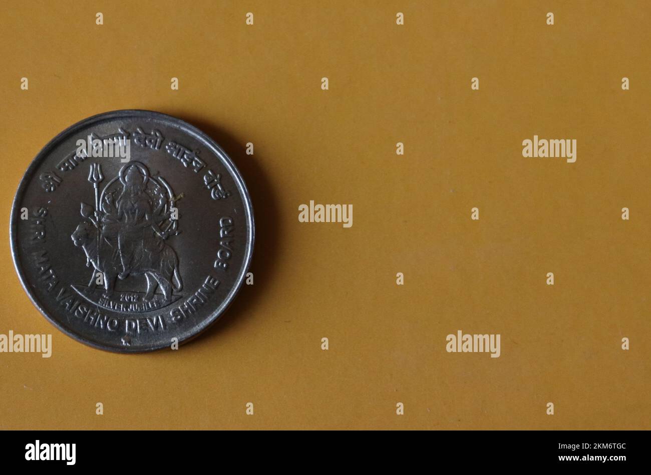 Close-up of Shree Mata Vaishno Devi coin against yellow background ...