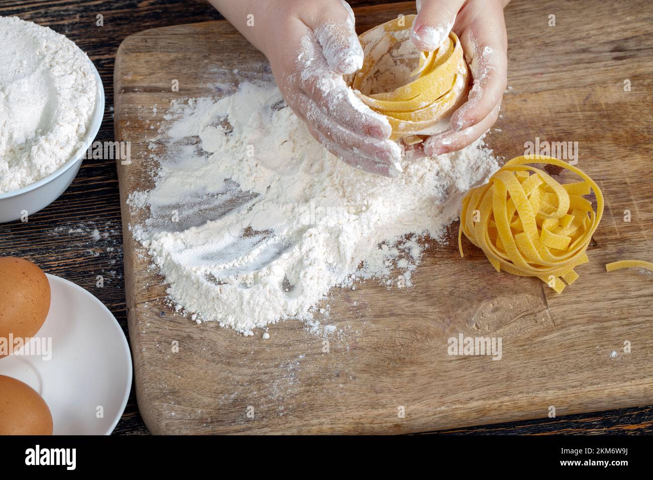 wheat flour pasta and wheat flour on a board, dry uncooked noodles with ...