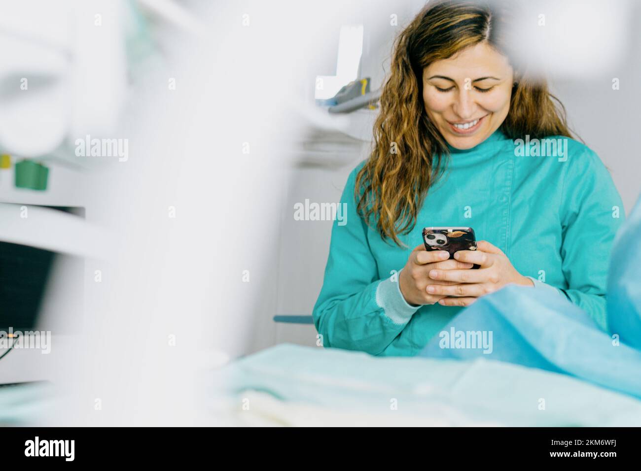 Smiling dentist in the operating room uses mobile phone Stock Photo - Alamy