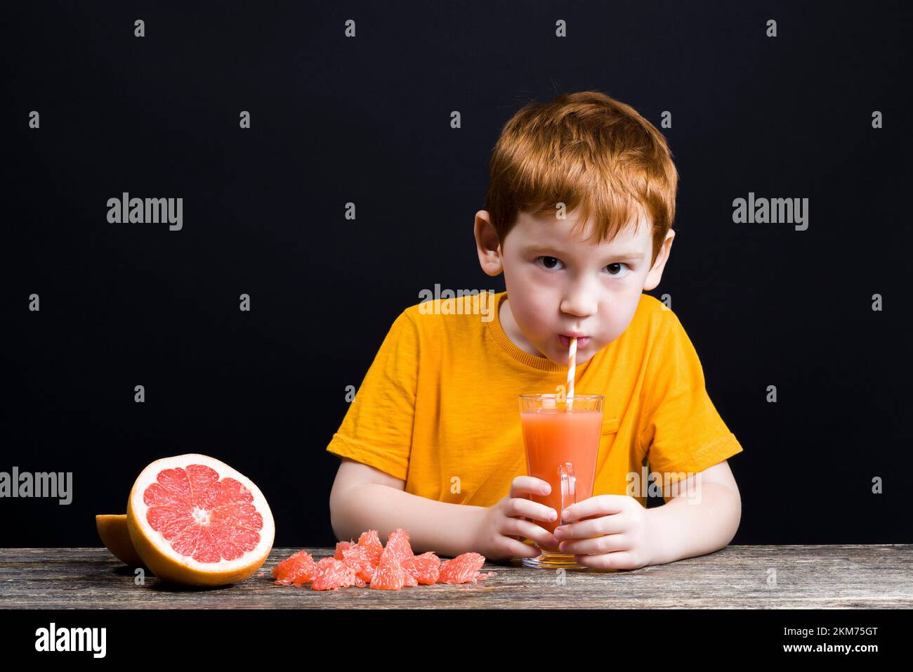 a very beautiful red haired boy with citrus fruit grapefruit from which ...