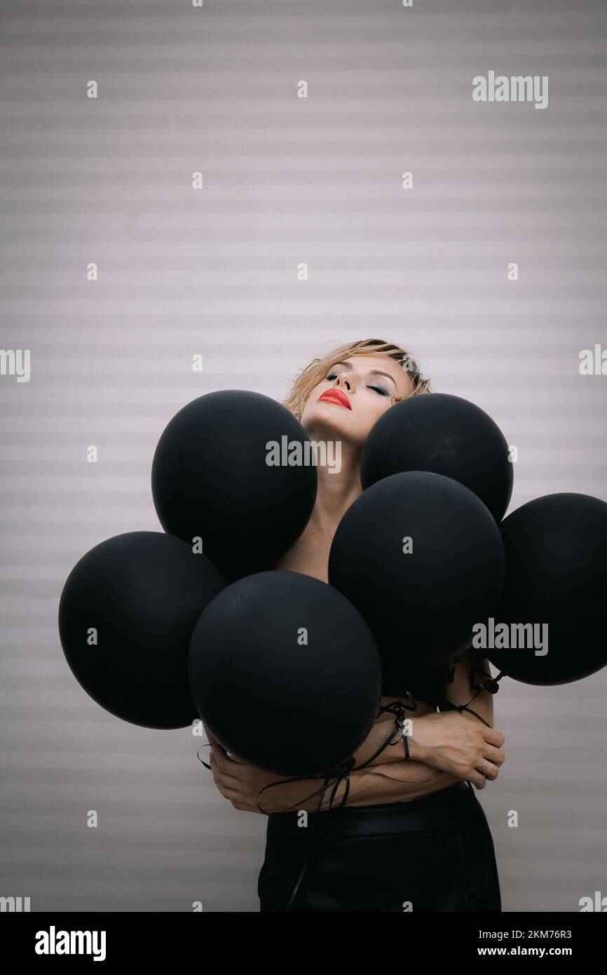 Beautiful woman of model appearance with dark balloons. Art shooting ...