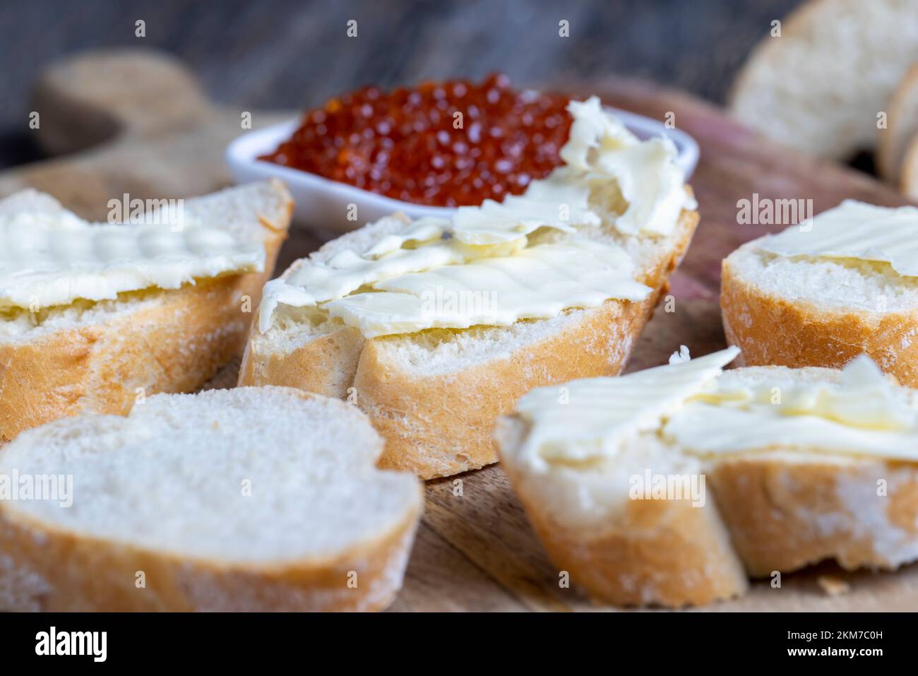 red salmon or trout caviar with white baguette and butter, making ...