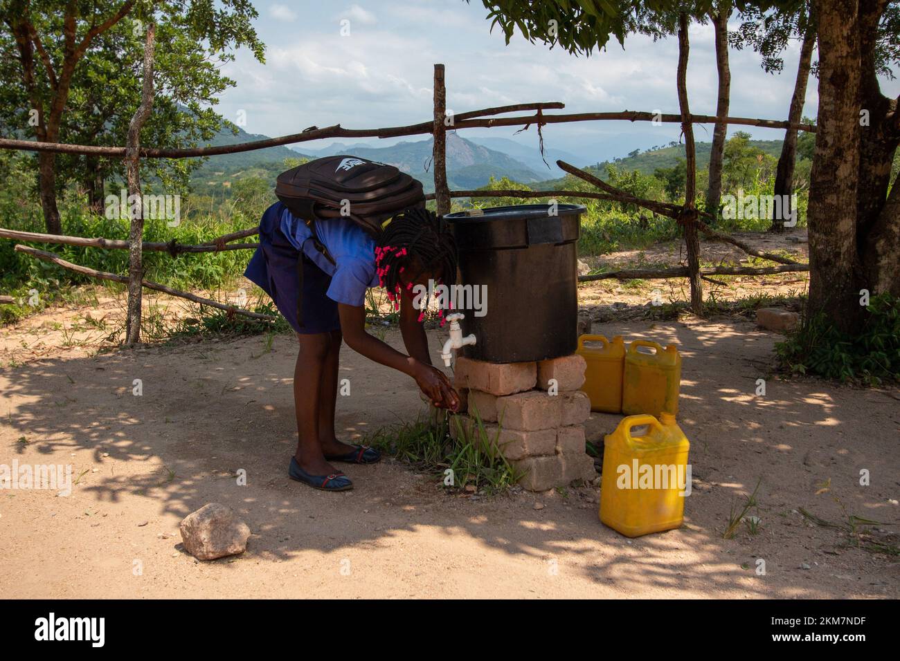 Young girl student washing her hands before her class using a gallon ...