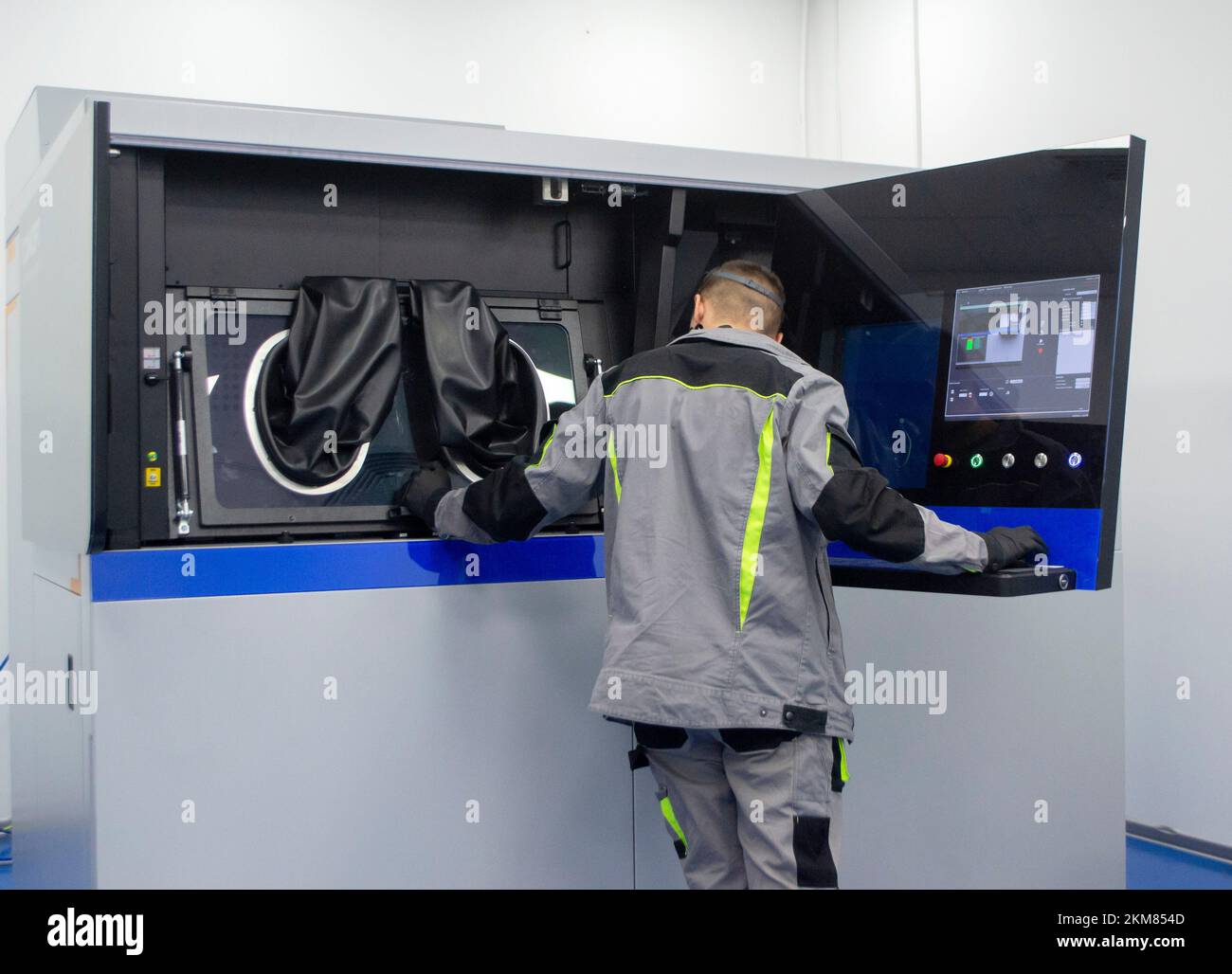 The worker controls workflow inside large industrial 3D printer ...