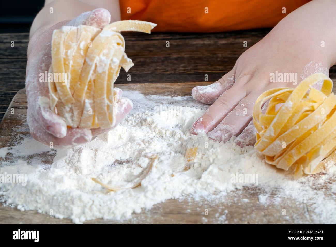 wheat flour pasta and wheat flour on a board, dry uncooked noodles with ...