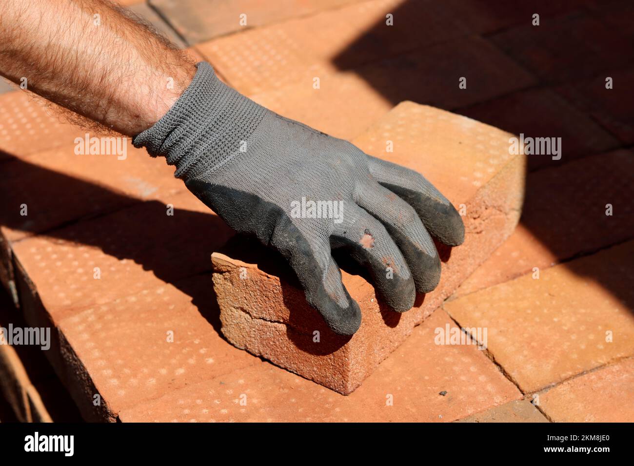Man's hand holding red brick. Construction and building works concept ...
