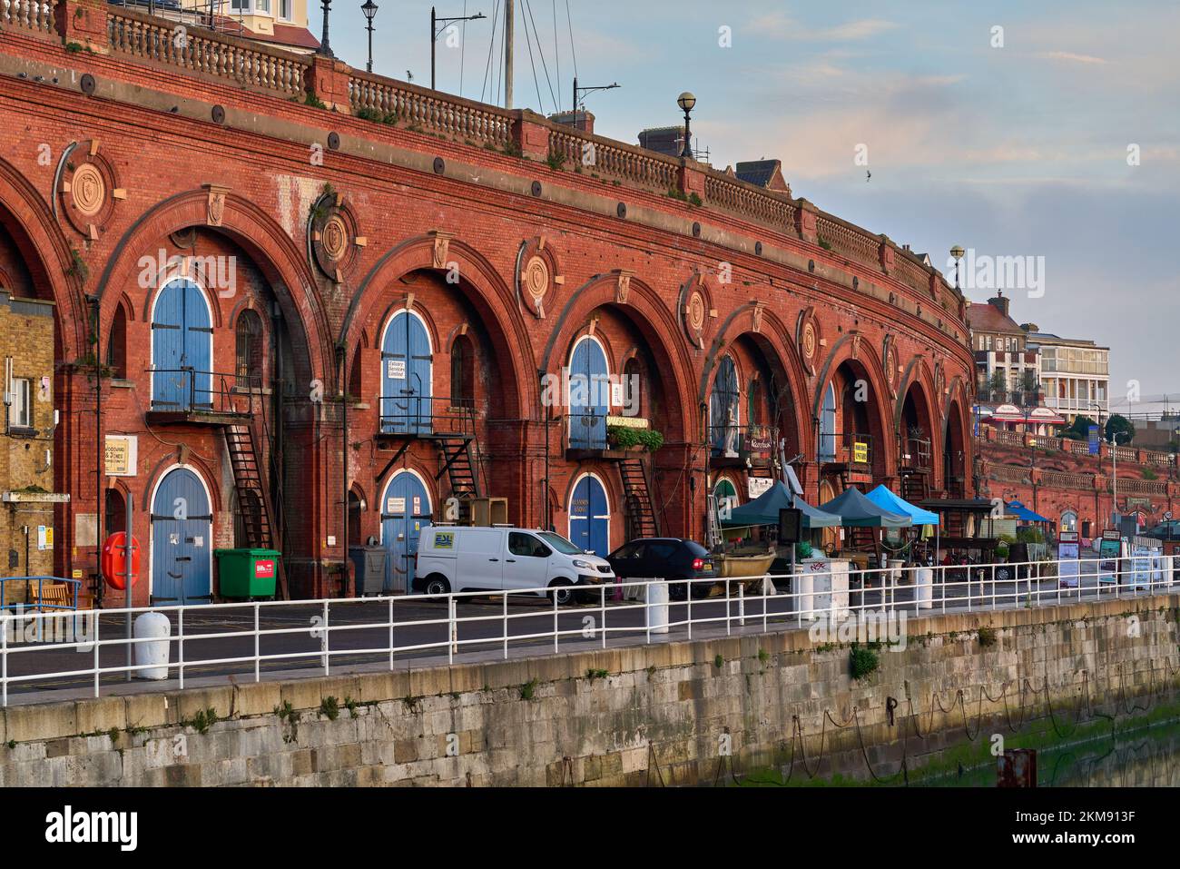 The facade of the Ramsgate Royal Harbour with red stone and arches in ...