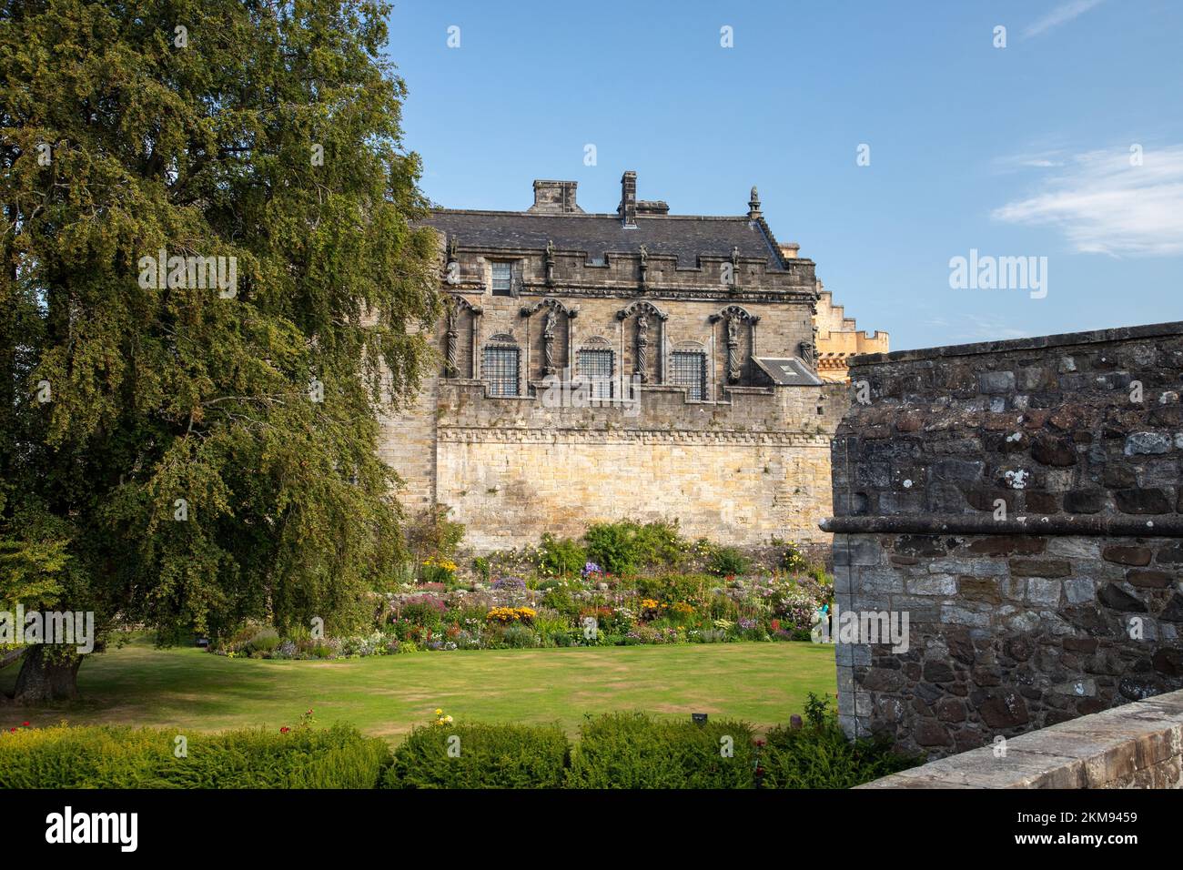 A facade of the Scotland castle with a green garden and lush greenery ...