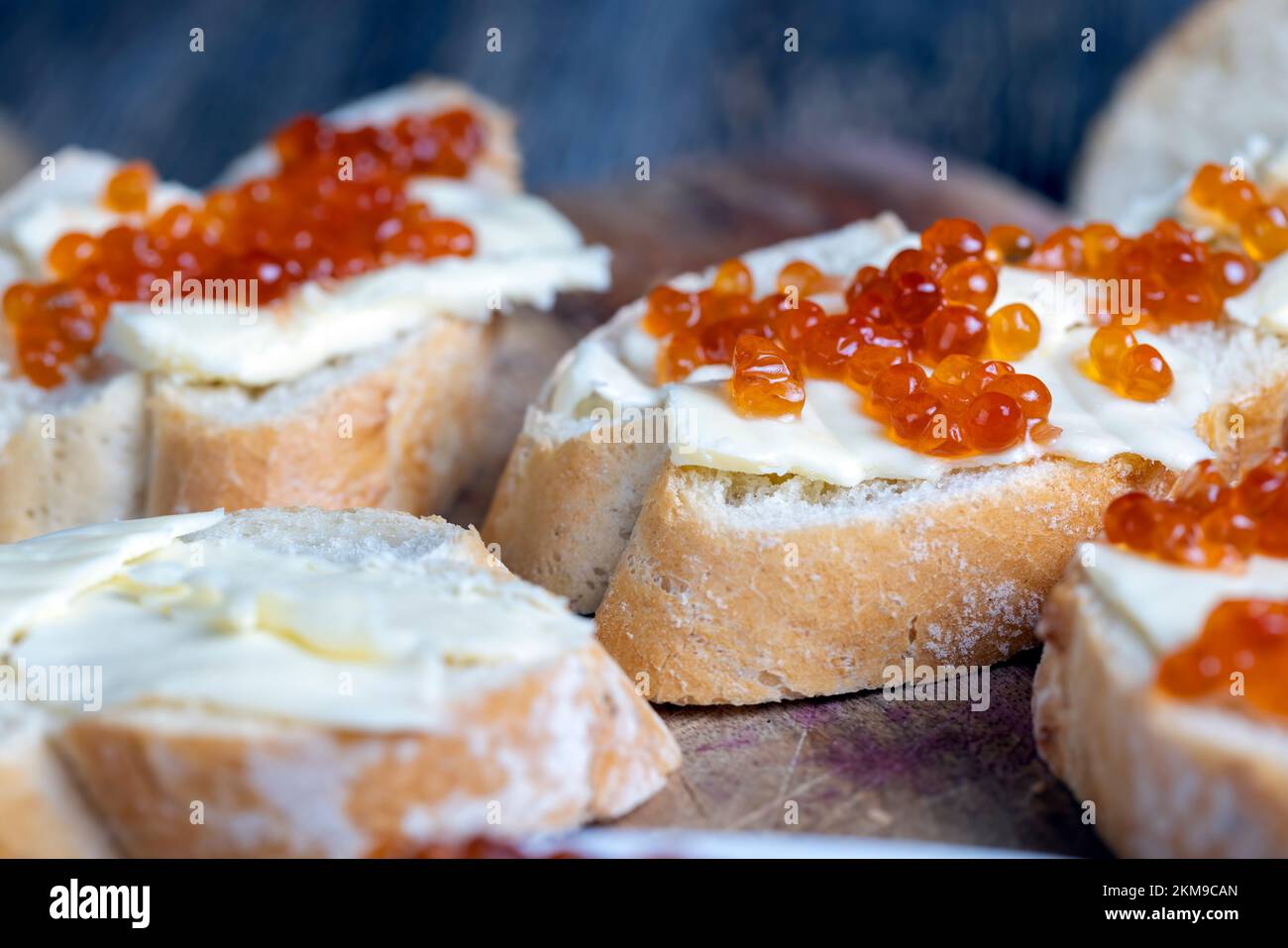 red salmon or trout caviar with white baguette and butter, making ...